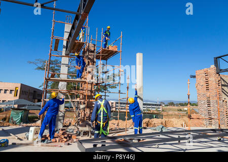 Brick layers passing bricks up to workers on a scaffolding in ...