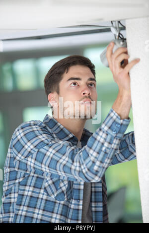 Man fitting cctv camera indoors Stock Photo - Alamy