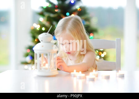 Beautiful little girl lighting a candle in white lantern on Christmas ...