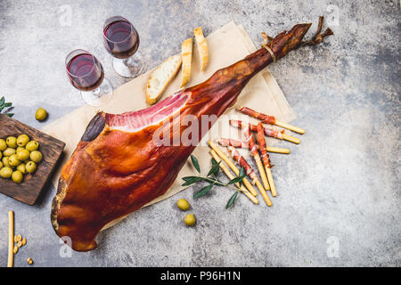 Whole leg of Spanish Iberian serrano ham hanging on a rope. On black ...