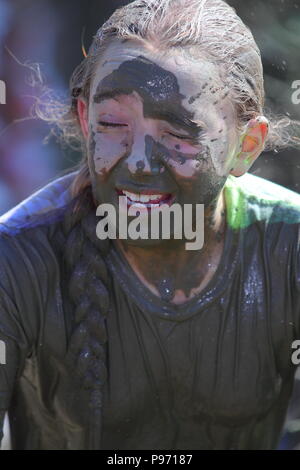 A young girl's face is completely covered in mud after participating in a local muddy obstacle ...