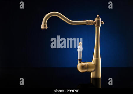 Modern kitchen faucet against dark blue background Stock Photo - Alamy