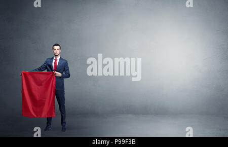Businessman standing with red toreador cloth in his hand in an empty ...