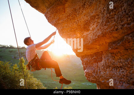 Picture of man clambering over rock Stock Photo - Alamy