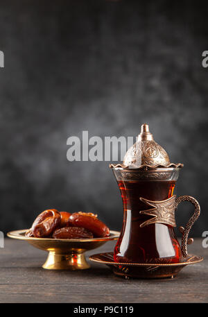 Saucer with glass of Turkish tea and dessert on table in room, closeup ...