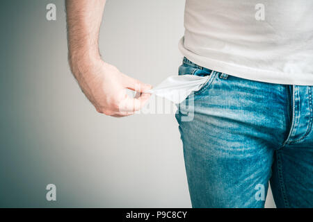 A man pulling out his trousers pockets to show that he has no money ...