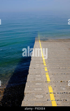 Concrete slipway on shingle beach with calm sea and horizon in ...