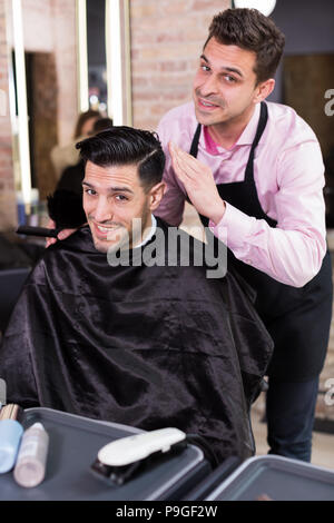 Portrait of skilled hairstylist and satisfied male customer after ...
