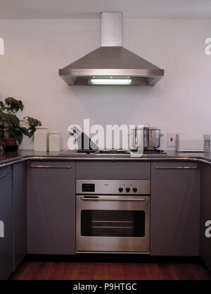 Stainless steel extractor fan above hob in modern white galley kitchen ...