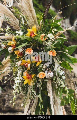Wedding arch on boho style with white flowers in park with light bulbs ...