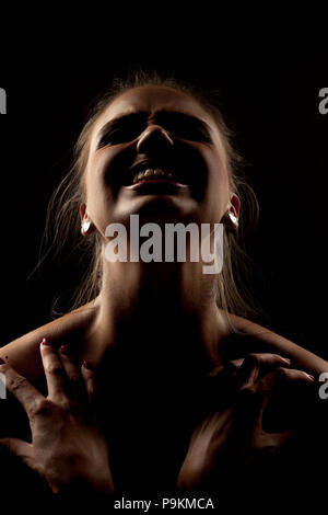 unknown woman with the face in the shadow holding finger on her lips on ...