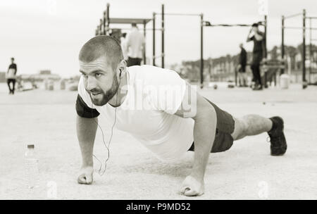 Strong man performs push-ups on an outdoor sports field Stock Photo - Alamy