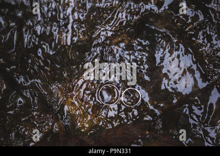 Wedding rings on water surface texture Stock Photo - Alamy