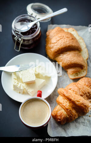 cup of fragrant coffee and croissants with butter on a wooden table ...