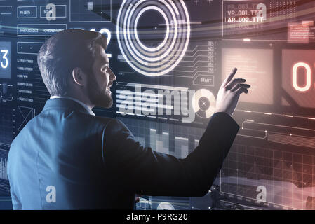 Positive web developer smiling and touching the transparent screen ...