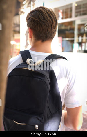 teenager with backpack is standing with his back on a meadow Stock ...
