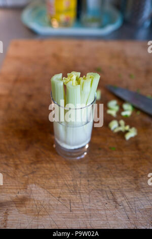 Chopped celery stalks, kitchen knife on cutting board. Basil sprigs and ...