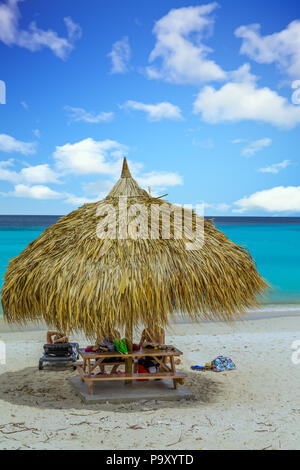 Straw hut on an idyllic beach with blue sky backdrop and white sand ...