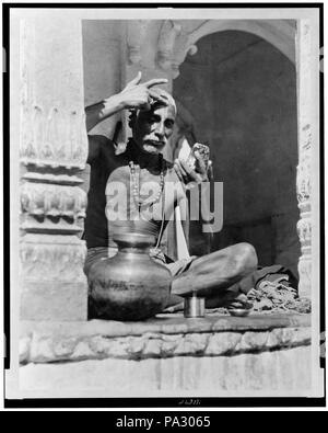 Brahman priest, in India, painting his forehead with the red and white ...