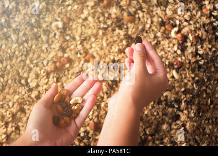 Female hand holds granola against the background of baking sheet with ...