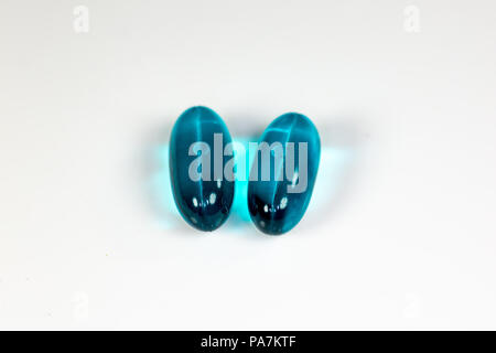 Two clear blue pills against the while surface of a pharmacy table ...