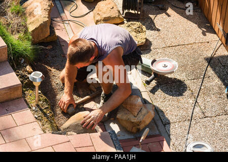 Workers build a stone wall at a site Stock Photo - Alamy