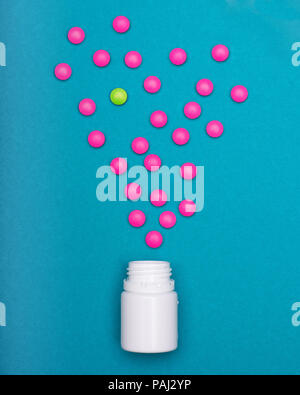 Heap of pink and blue pills on colored background. Tablets scattered on ...