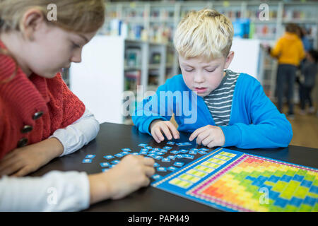 Pupils playing a board game in school library smiling at each other ...