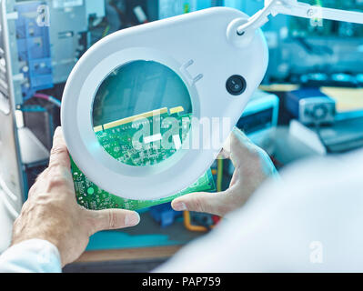 Circuit board testing. Technician checking a circuit board under a ...