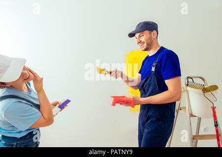 Couple having fun while coloring their room in yellow color Stock Photo ...