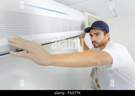 tech guy carefully installing new ac Stock Photo - Alamy