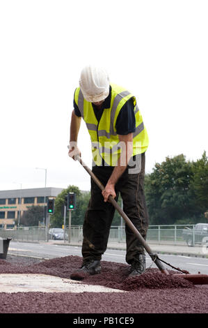 A workman raking out his red asphalt in the UK Stock Photo - Alamy