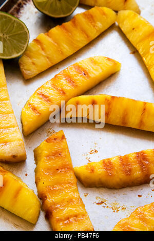 Grilled pineapple with lime on tray over black background, overhead ...