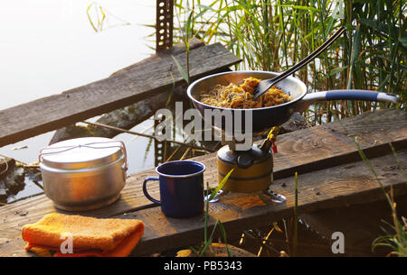 Camping food making. Pasta on pan on tourist fire stove. Camp cooking ...