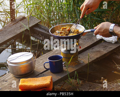 Camping food making. Pasta on pan on tourist fire stove. Camp cooking ...
