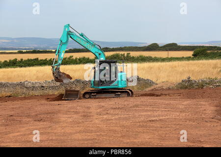 A newly commisioned large tracked digger levelling off the earth in a ...