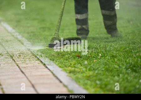 Law mower man trimming grass in the city Stock Photo - Alamy