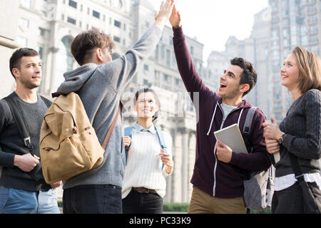 Young abroad students high fiving Stock Photo - Alamy