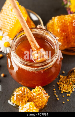 Honey jar and dipper with leaking honey Stock Photo - Alamy