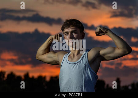 Teenage boy flexing his muscles at a high school track & field meet ...