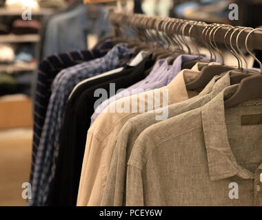 A closeup shot of colorful T-shirts on hangers in a row in a shopping ...