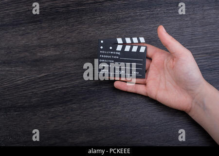 Hand holding movie clapper on a dark background Stock Photo - Alamy