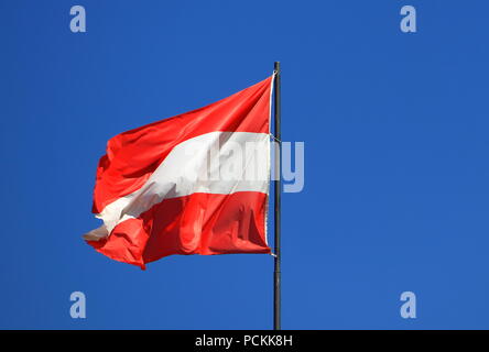 Bright red-white-red flag of austria against a clear sky on a sunny day ...