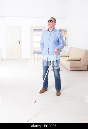 Blind man with white stick and dark glasses at home Stock Photo - Alamy