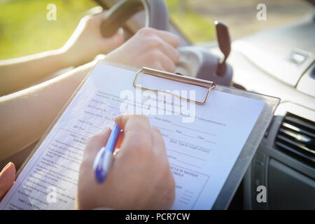 Examiner filling in driver's license road test form sitting with her ...