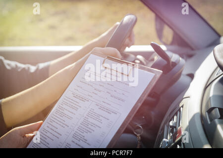 Examiner filling in driver's license road test form sitting with her ...