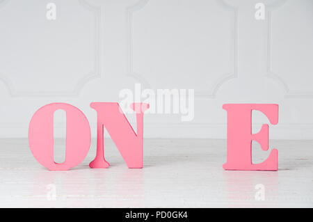 Large pink letters ONE against a white brick wall Stock Photo - Alamy
