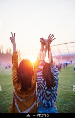 Two young women making peace signs and piggybacking Stock Photo ...