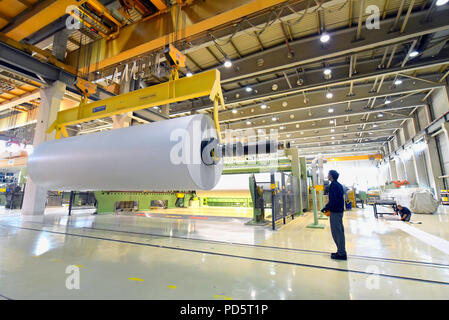 large roll of paper on a crane in a mill for the production of paper ...