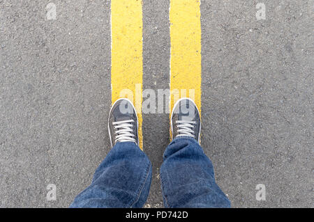 Personal perspective of person's legs and street's yellow lines Stock ...